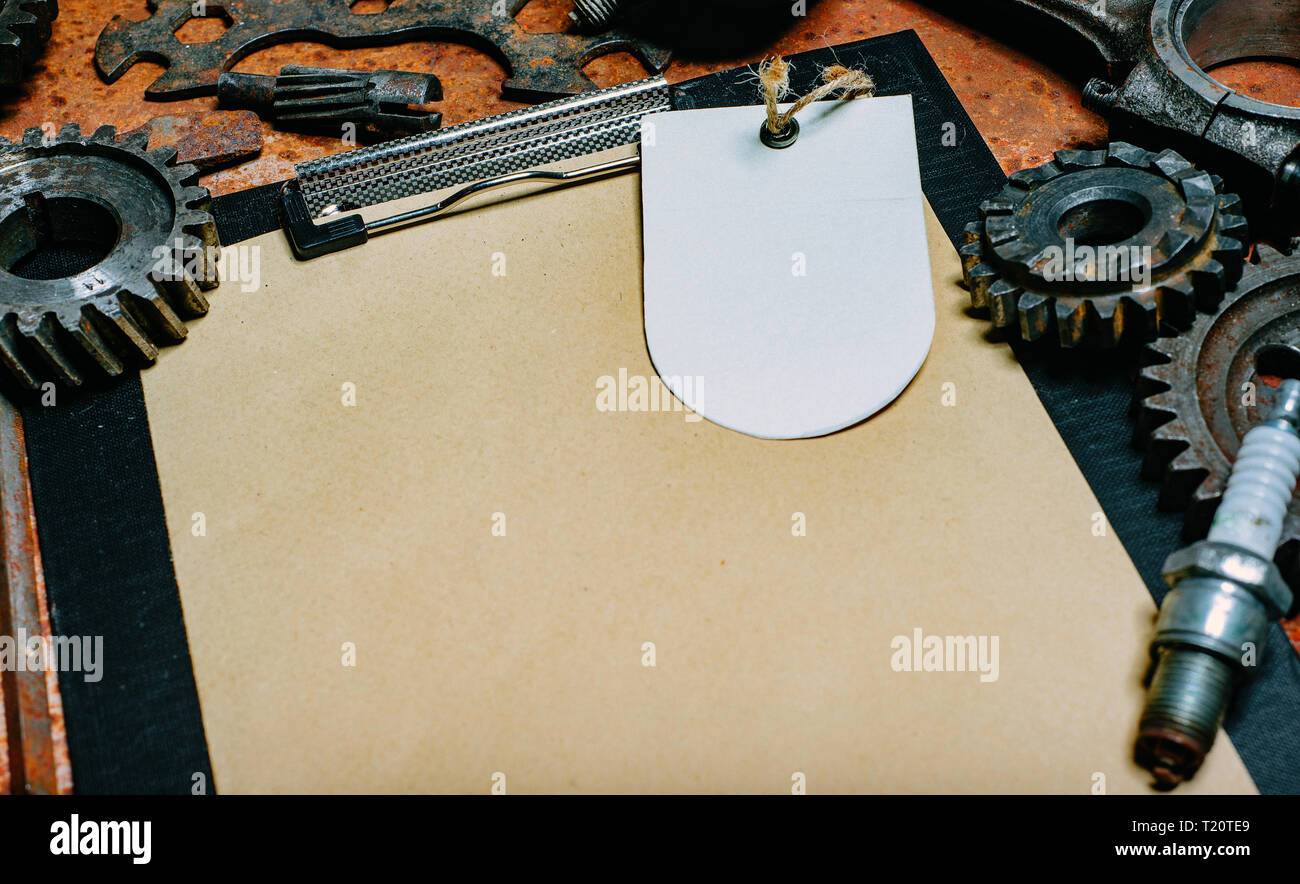 Part of closeup clipboard with paper and label. Rusty tools, gears ...