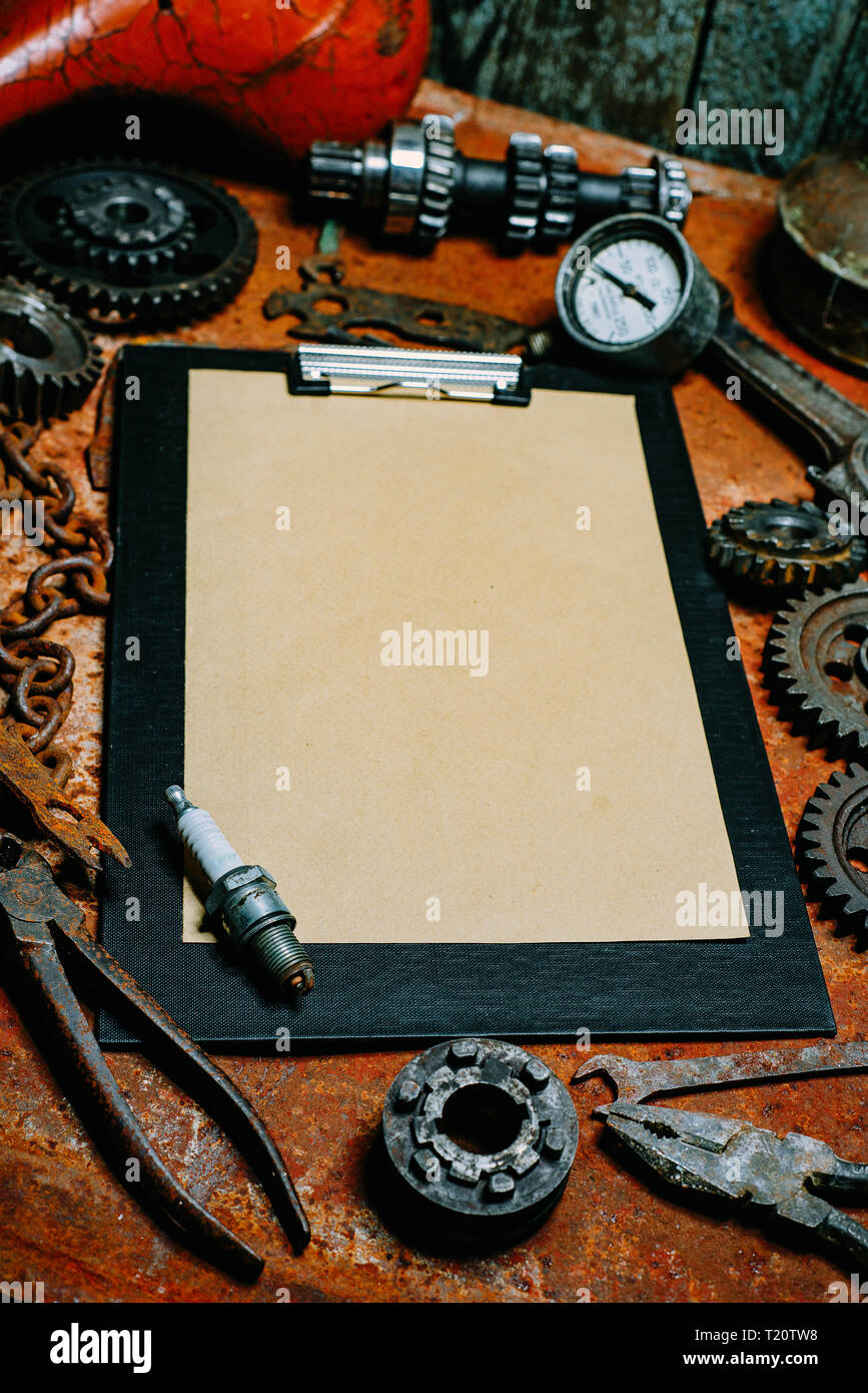 Clipboard with vintage paper in the center of rusty tools, gears on old ...