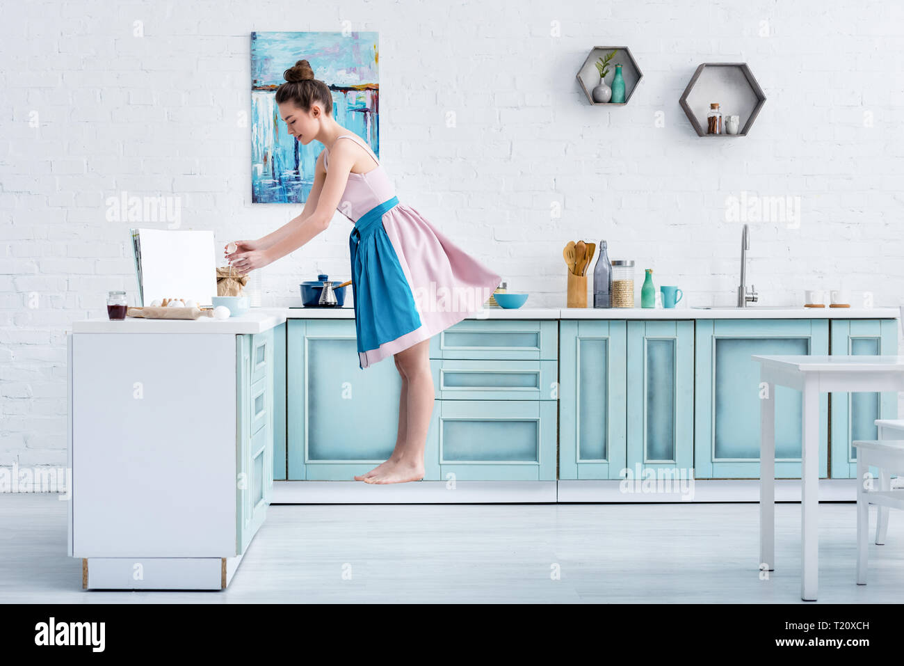 young barefoot woman levitating in air while cooking in kitchen Stock ...
