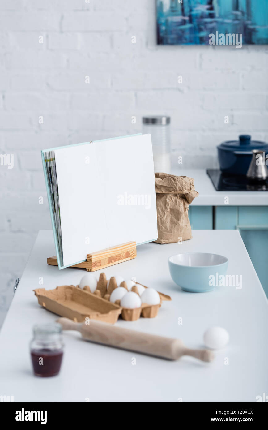 empty opened cookbook on table with cooking utensils and bakery ...