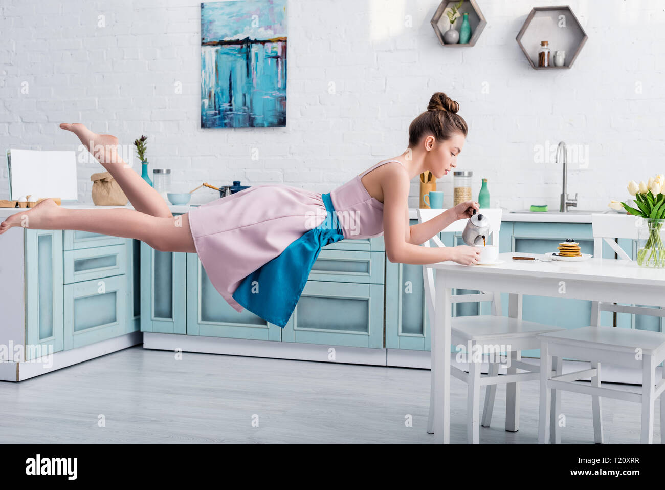 beautiful young woman levitating in air and pouring tea in cup from ...