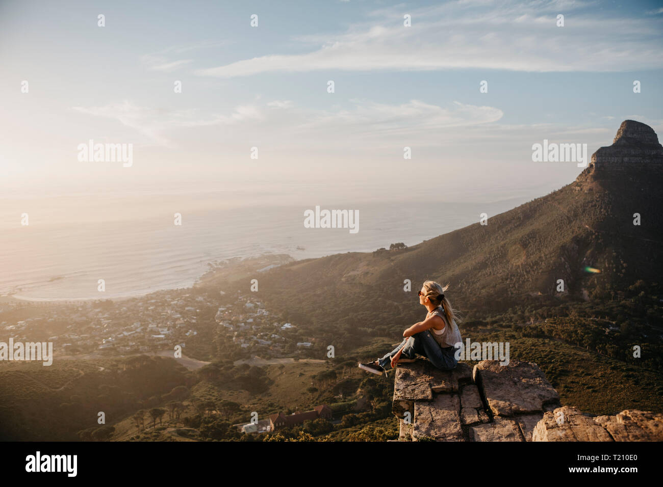 South Africa, Cape Town, Kloof Nek, woman sitting on rock at sunset ...