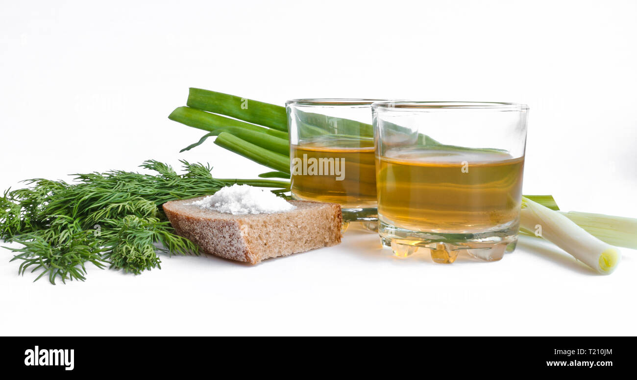 Pepper vodka in two transparent glasses, green onions, dill, rye bread ...