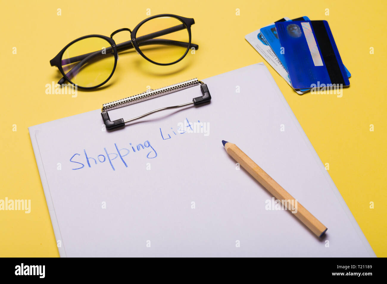 List of paper with words shopping list, credit cards, pen on yellow ...