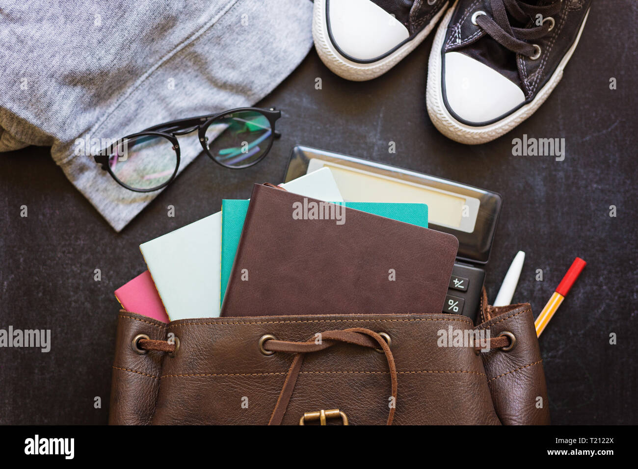 Backpack with school stationery and glasses on slate background. Back ...