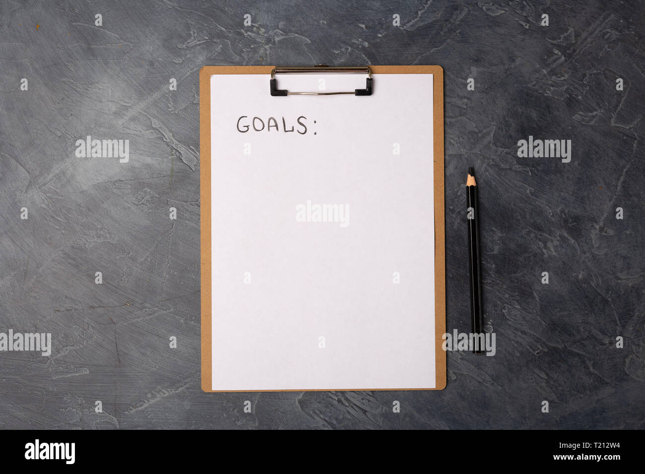 Blank paper with goals title and black pencil on grey table. Flat lay ...