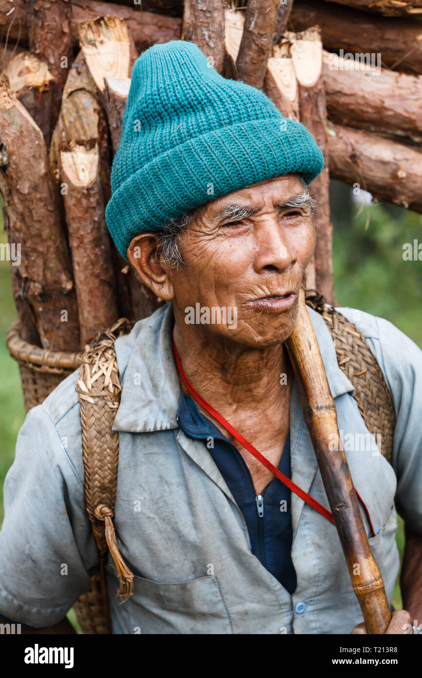 Closeup of 87 year old village man with turquoise knit hat carries a ...