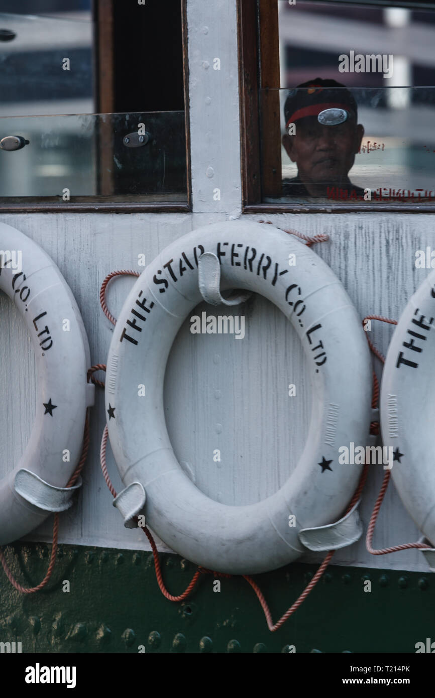 A Star Ferry employee looks out from the window of the ferry, with life ...