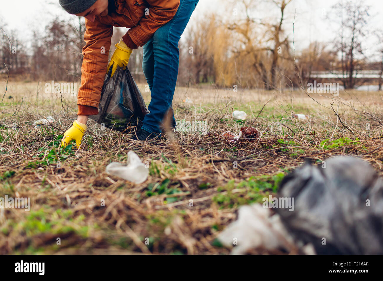 Man volunteer cleaning up the trash in park. Picking up litter outdoors ...
