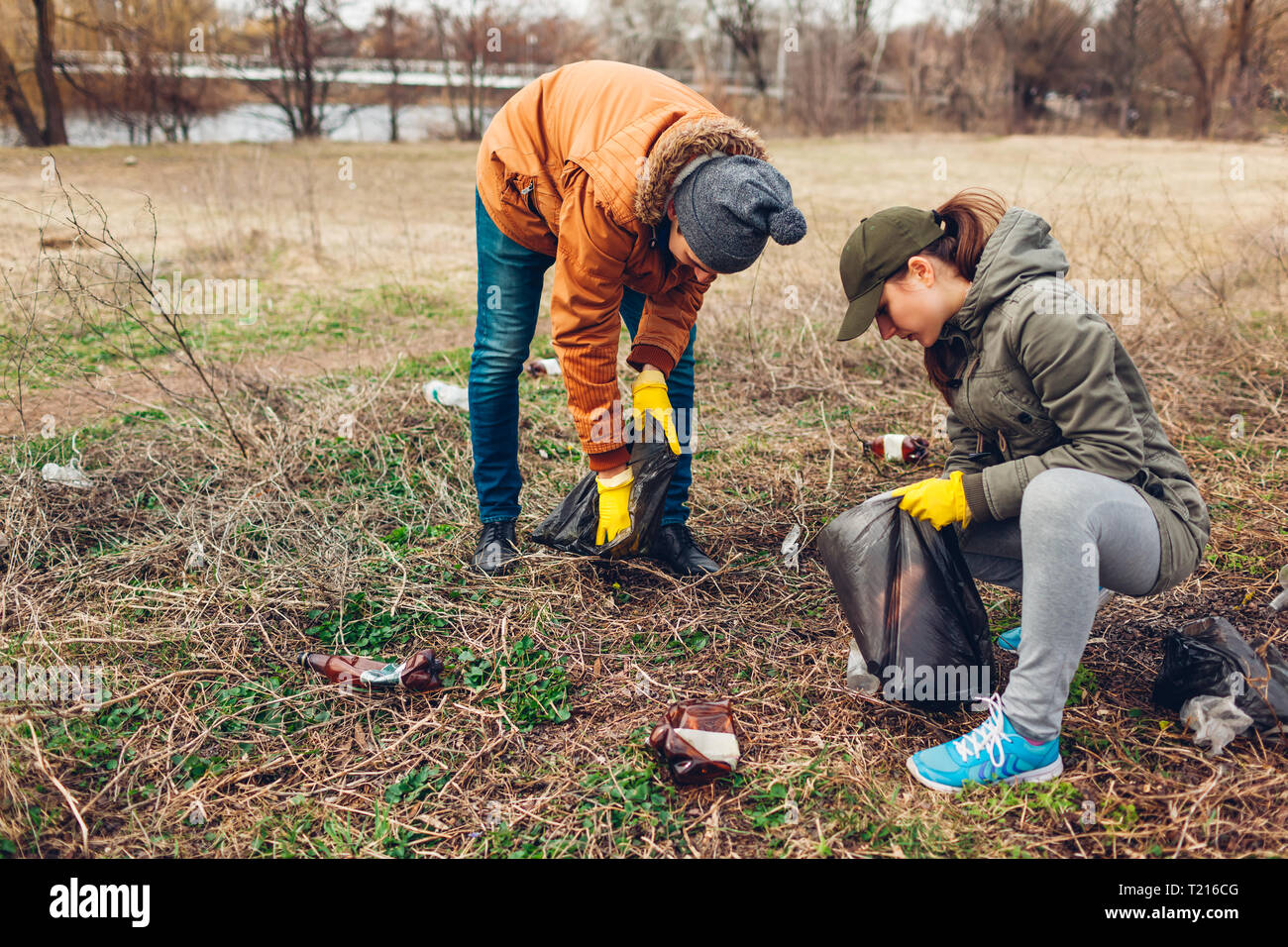 Couple of volunteers cleaning up the trash in park. Picking up garbage ...