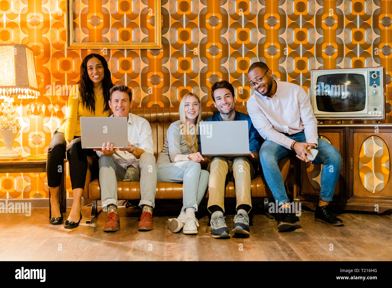 Group of smiling people sitting on couch in vintage living room with ...