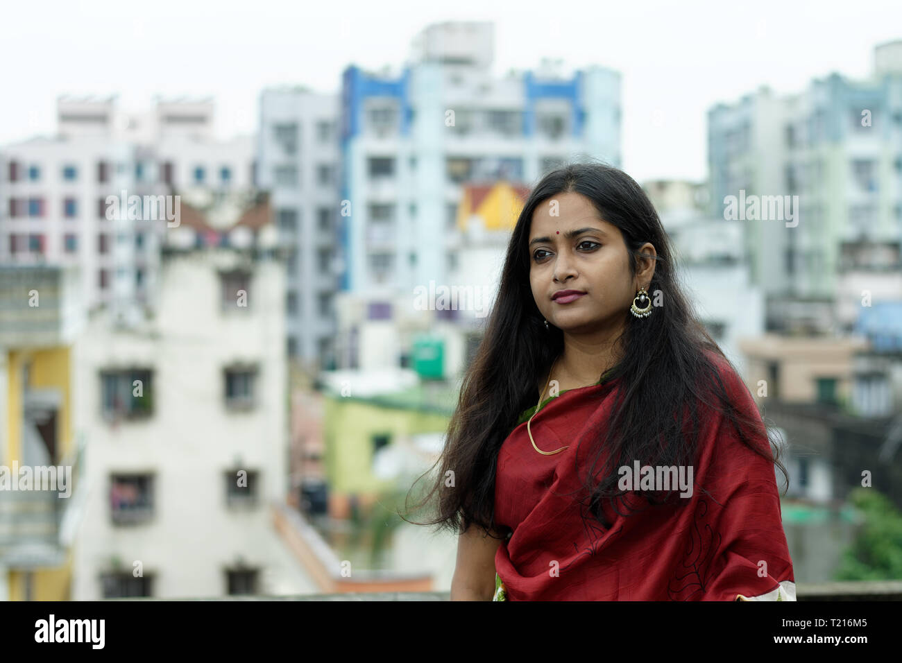 Beautiful Indian Bengali lady in glowing red sari is standing on ...