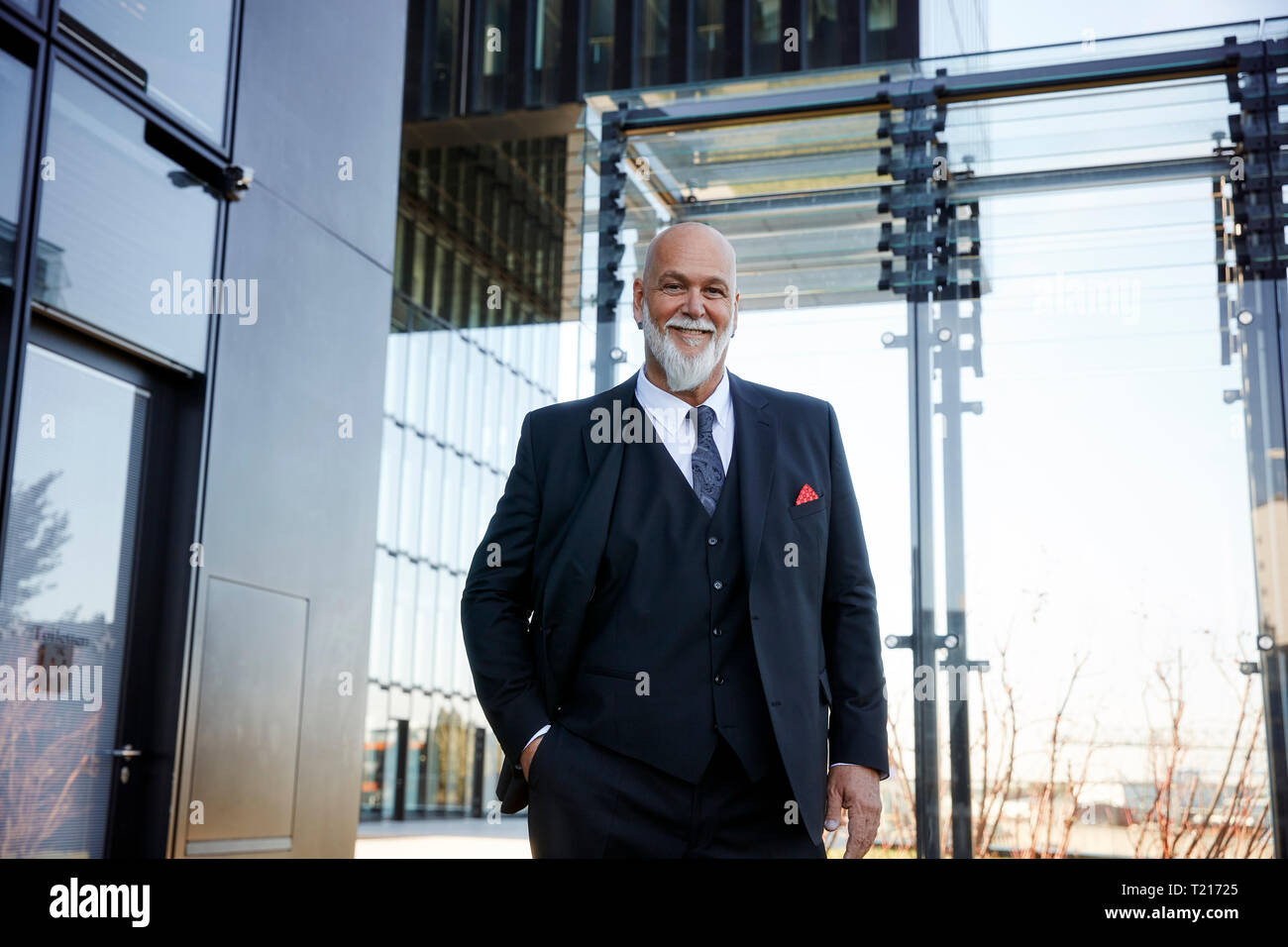 Elegant businessman standing in front of office building, smiling Stock ...