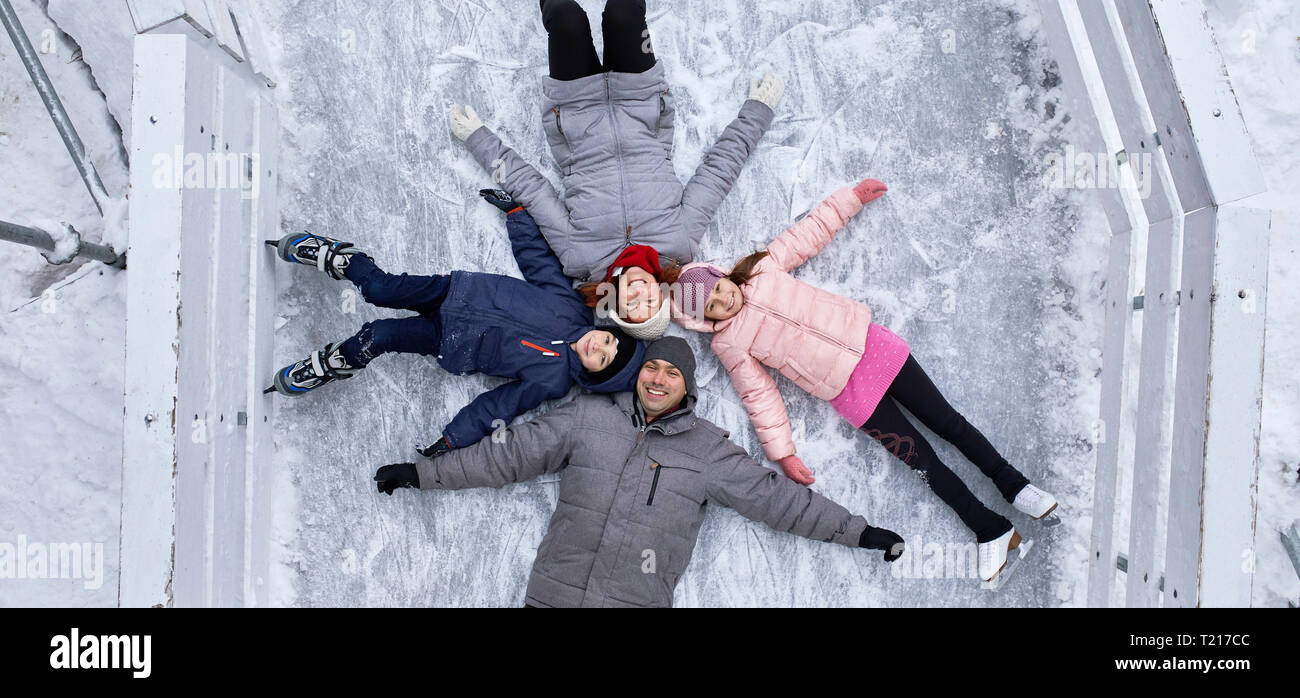 Family with two kids on the ice rink, lying on the ice Stock Photo - Alamy