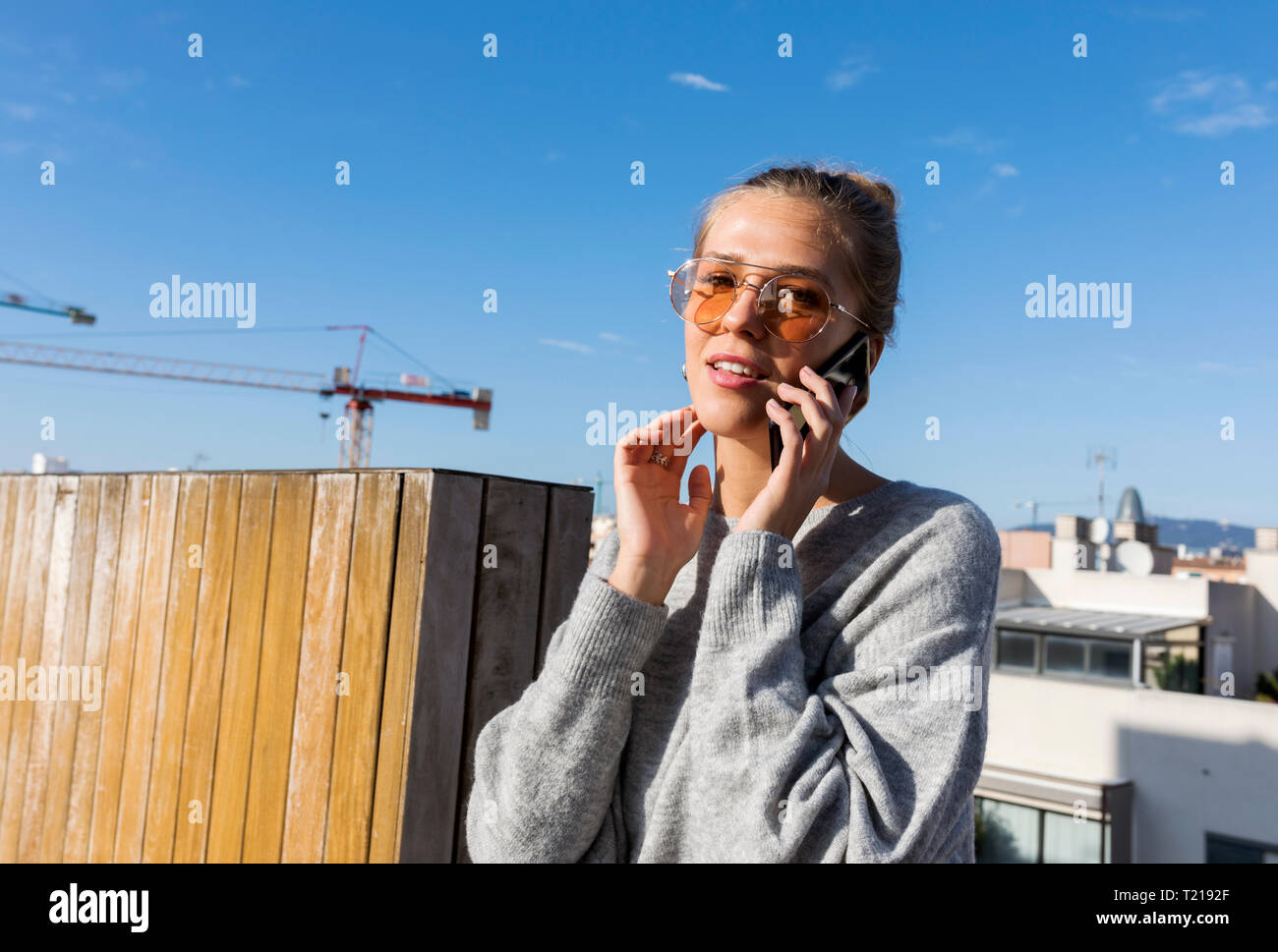 Young woman using smartphone on an urban rooftop terrace Stock Photo ...