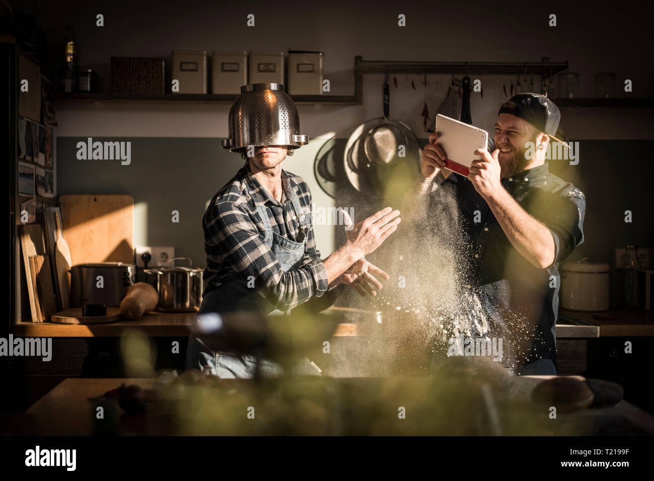 Young man filming his friend, wearing a colander as helmet in the ...