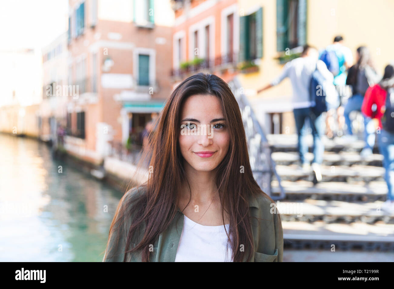 Italy, Venice, portrait of smiling young woman in the city with canal ...