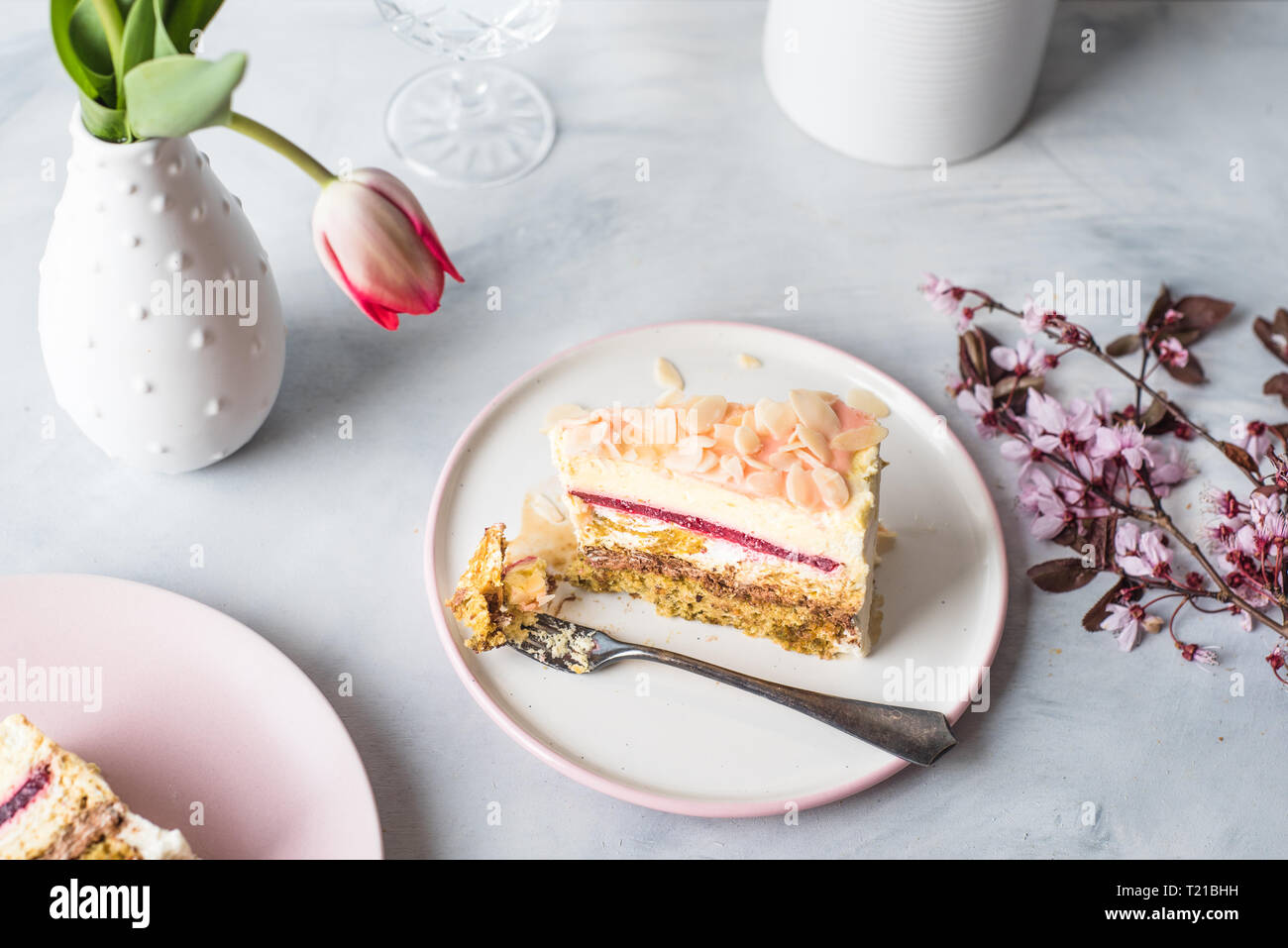 A slice of chocolate mousse cake on a white plate and a tulip flower in ...