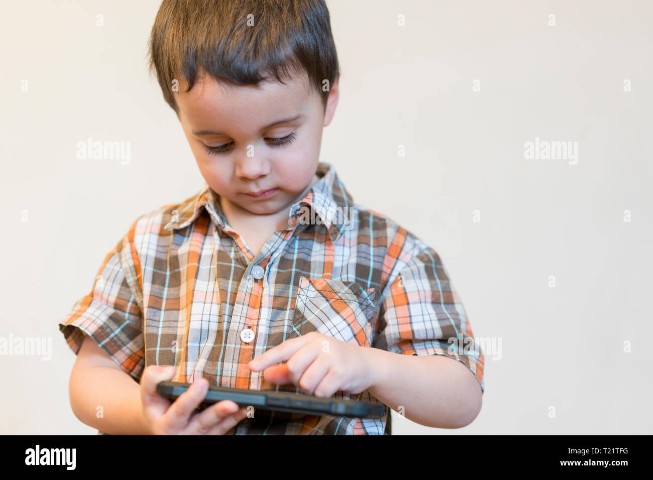 Portrait of a smiling little boy holding mobile phone isolated over ...