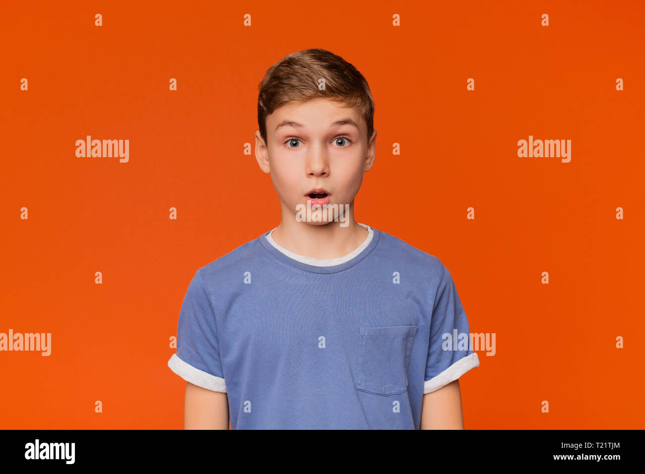 Portrait of stunned shocked little boy on orange studio background ...