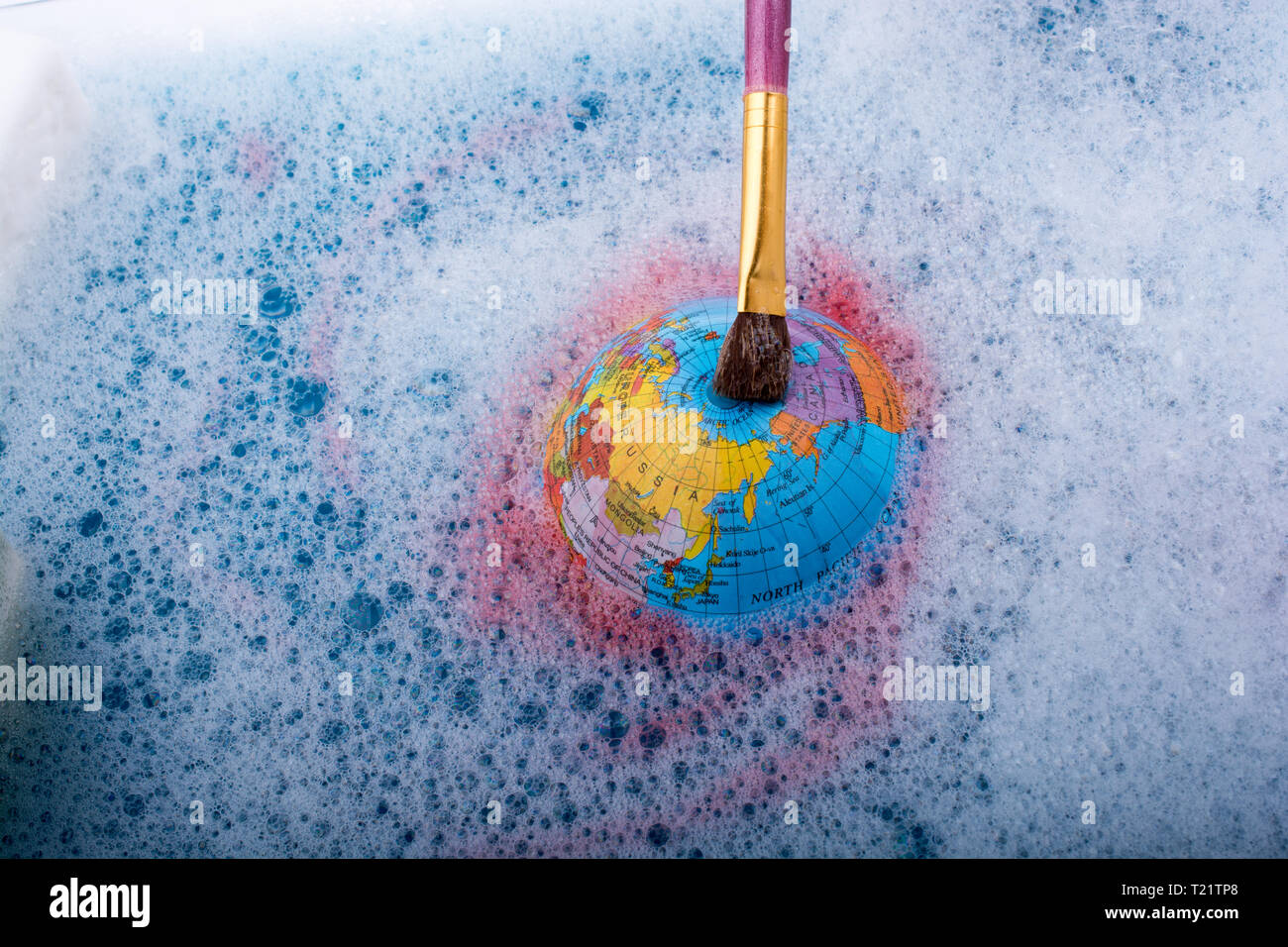 Paint dissolving through painting brush on the top of globe Stock Photo ...