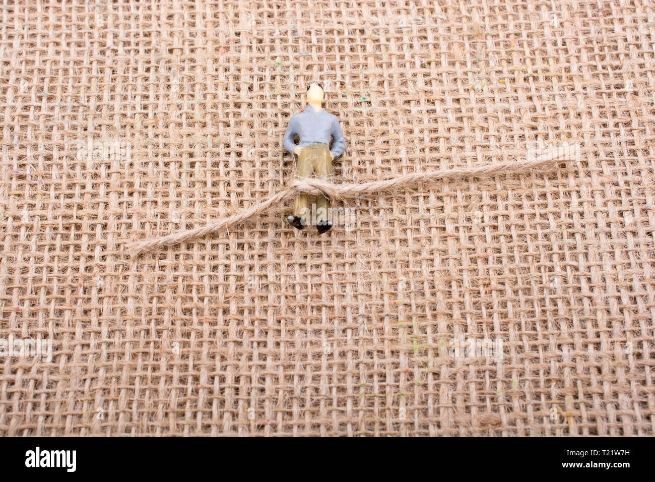 Figurine man with a rope on the legs Stock Photo - Alamy