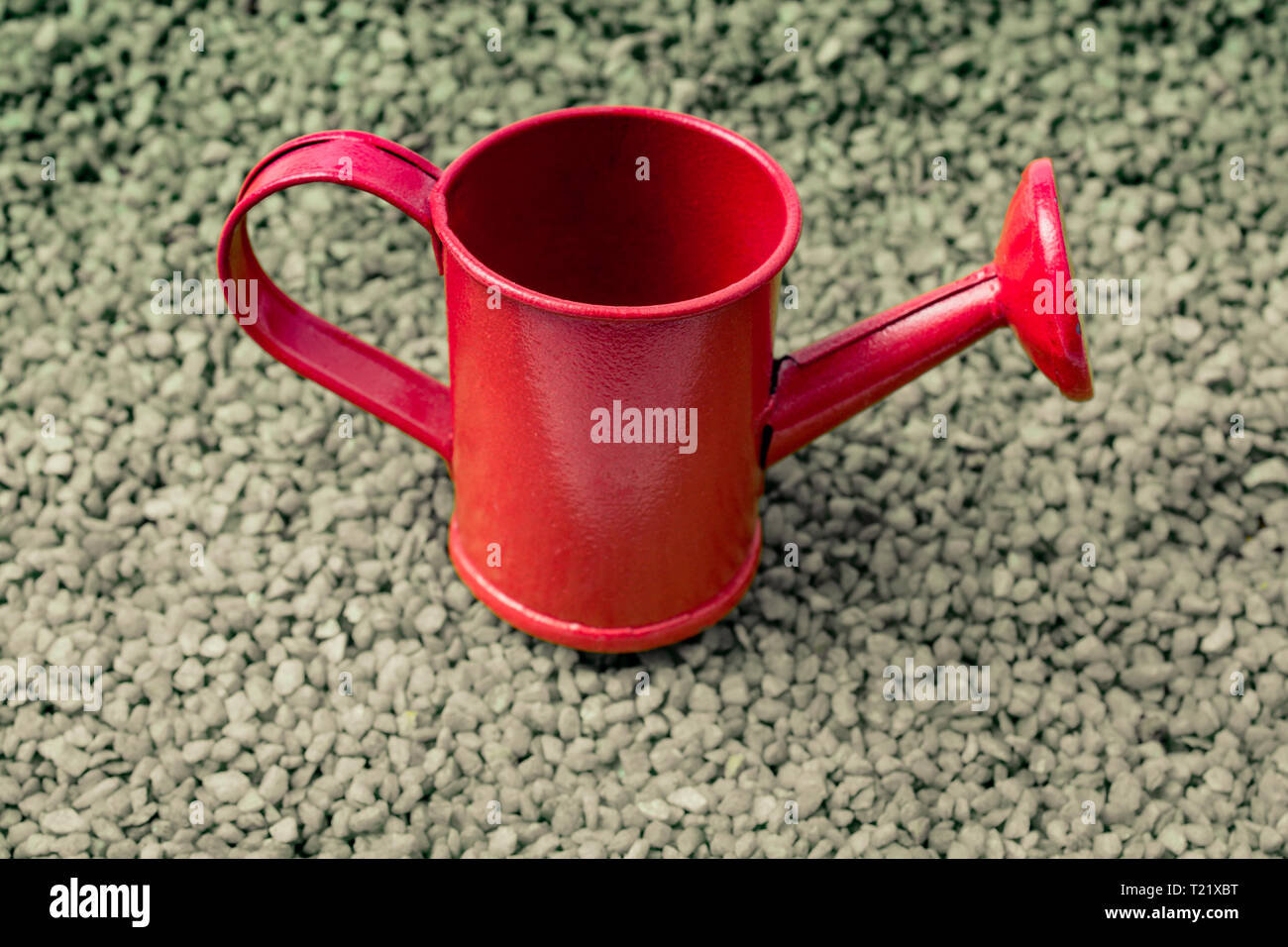 Little red color watering can on green sand Stock Photo - Alamy