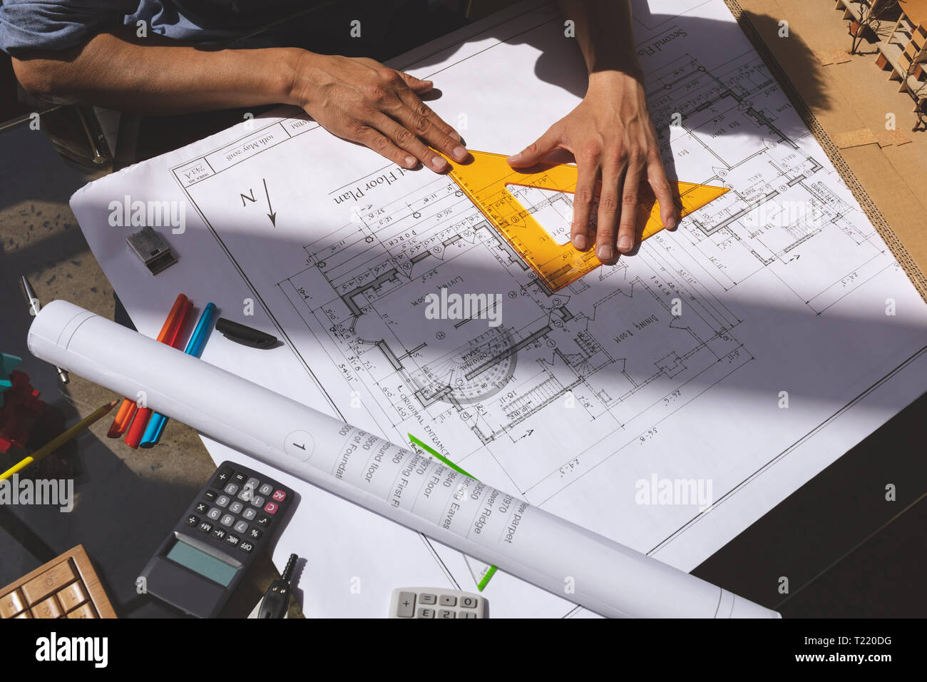 Male architect working on blueprint at desk in a modern office Stock ...
