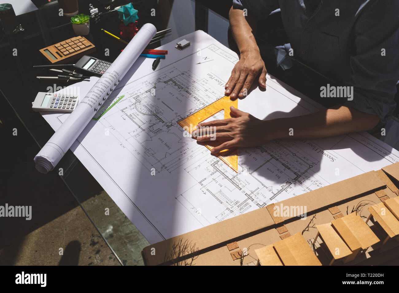 Male architect working on blueprint at desk in a modern office Stock ...