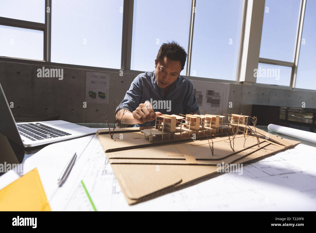 Male architect working on architectural model at desk in a modern ...