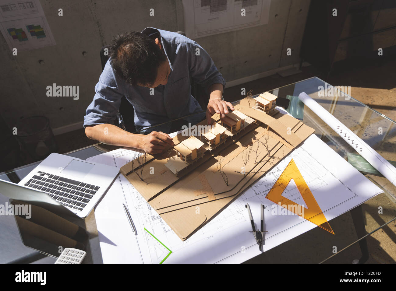 Male architect working on architectural model at desk in a modern ...