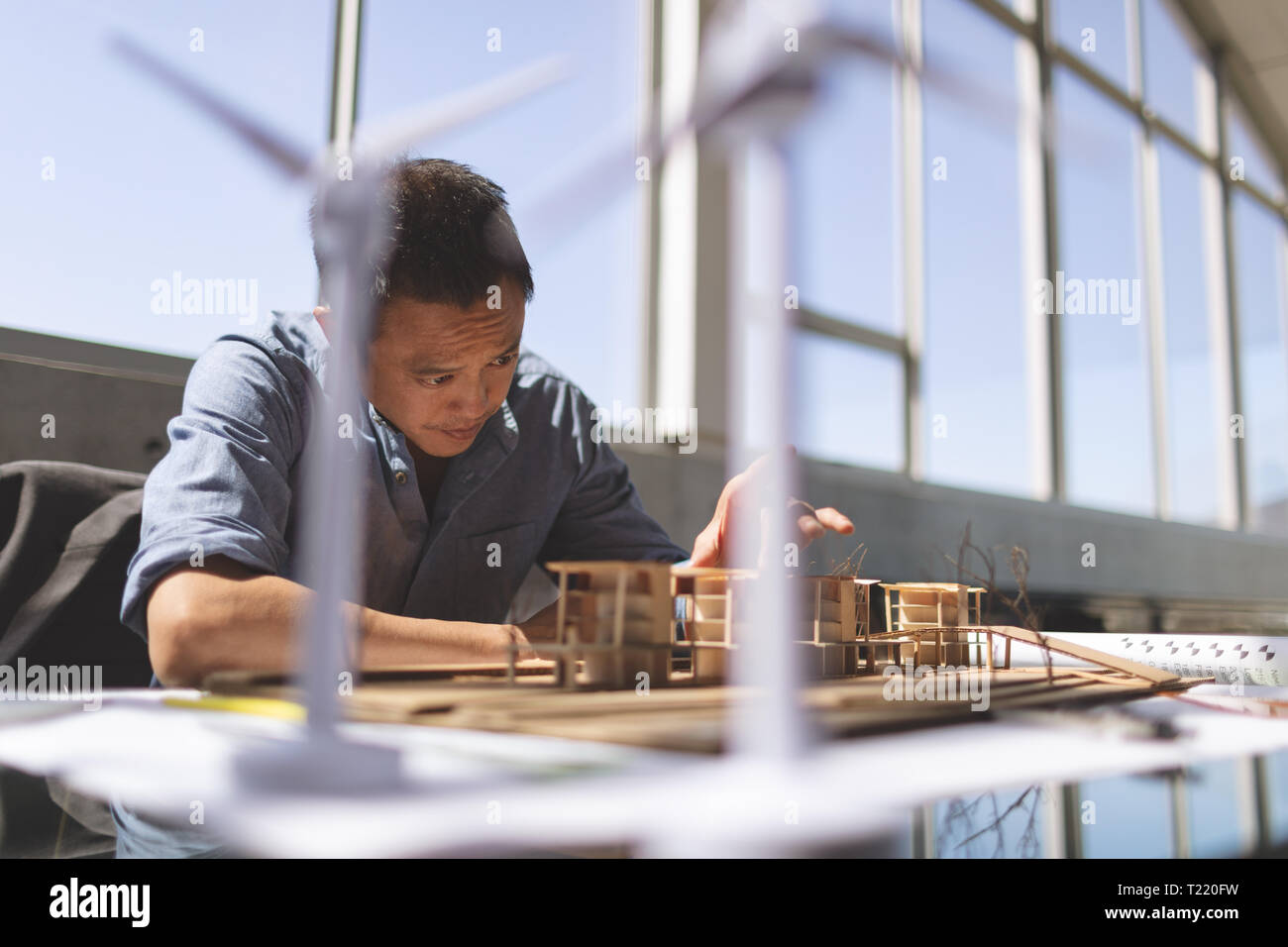 Male architect working on architectural model at desk in a modern ...