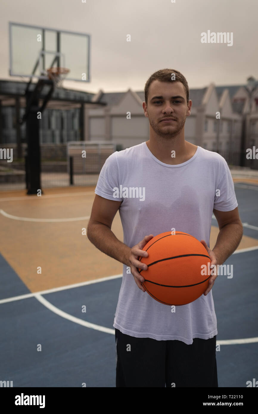 Man holding a basketball standng in playground Stock Photo - Alamy