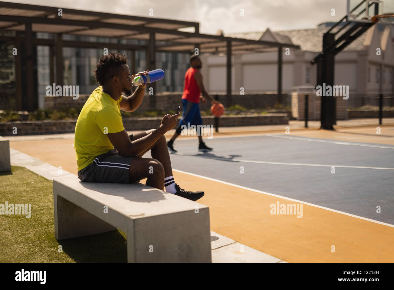 Basketball player drinking water while relaxing at basketball court ...