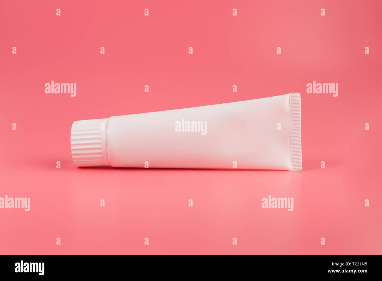Blank white tube of toothpaste, cream or gel laying on pink background ...