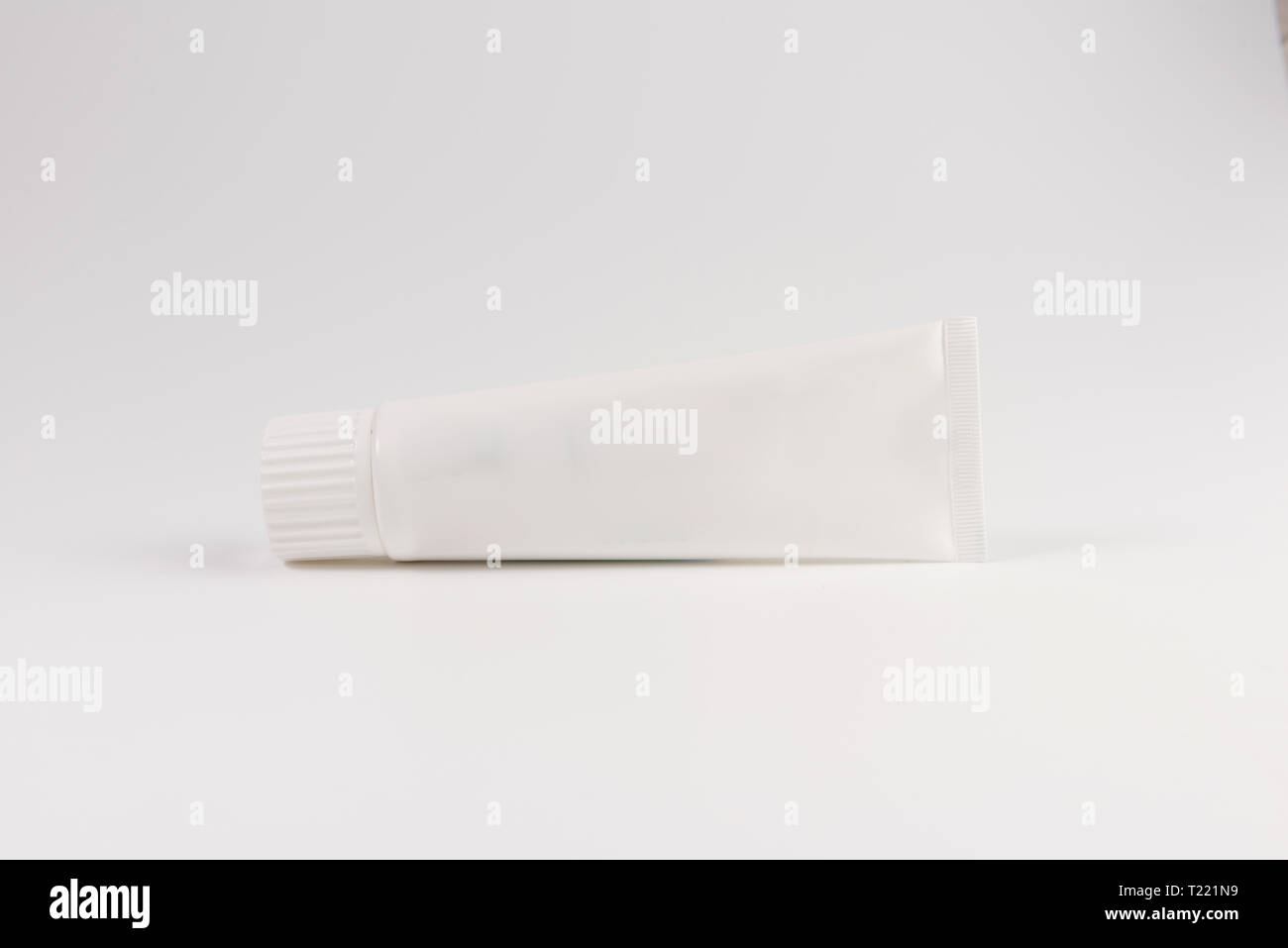 Blank white tube of toothpaste, cream or gel laying on white background ...