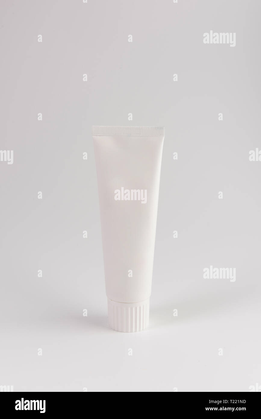 Blank white tube of toothpaste, cream or gel standing on white ...