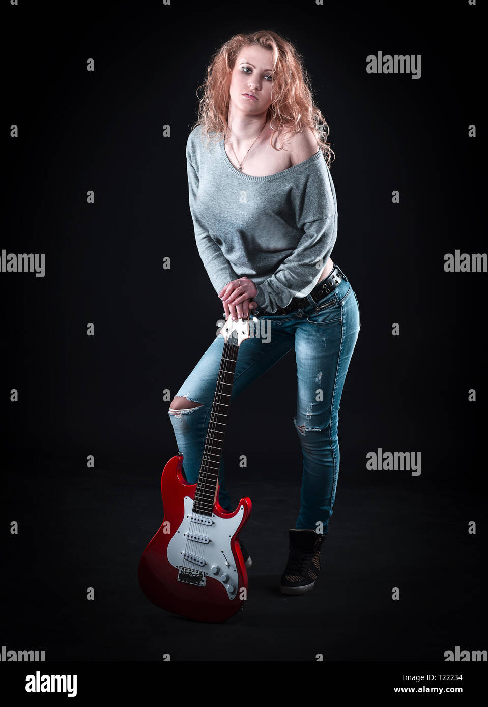 rock singer with a guitar standing on the stage . isolated on a dark ...