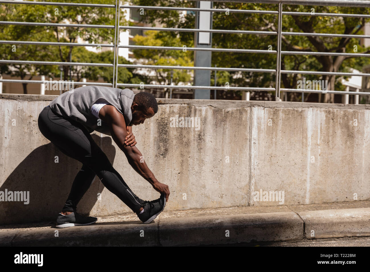 Man doing stretching exercise on side walk Stock Photo - Alamy