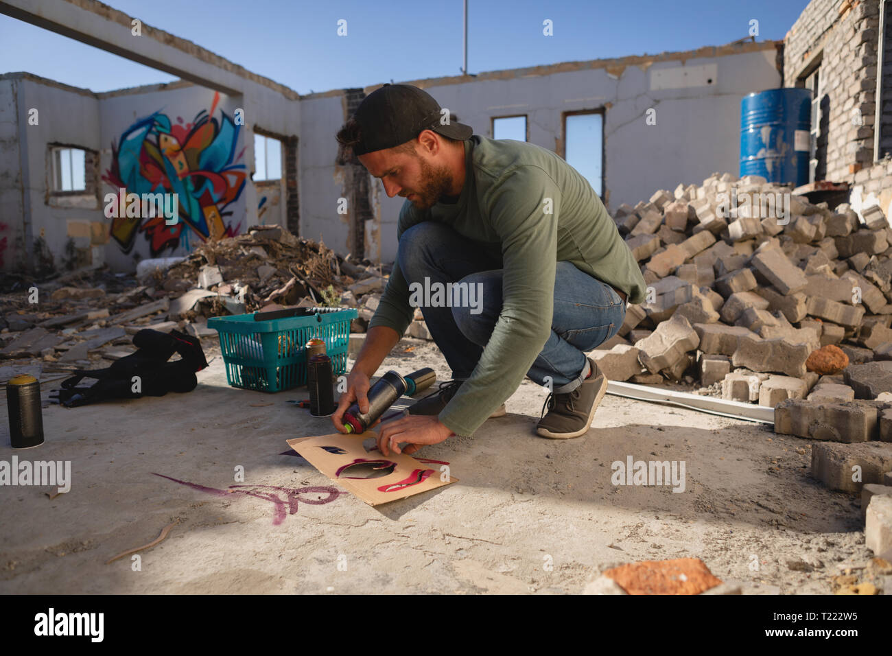 Graffiti artist spray painting on card board at alley Stock Photo - Alamy