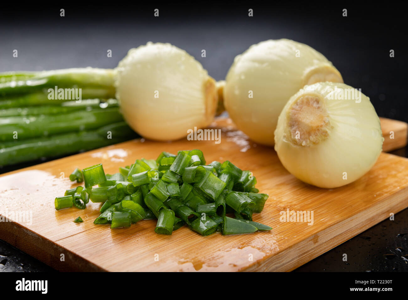 Fresh wet young onion on the kitchen table. Sliced chives on a kitchen ...
