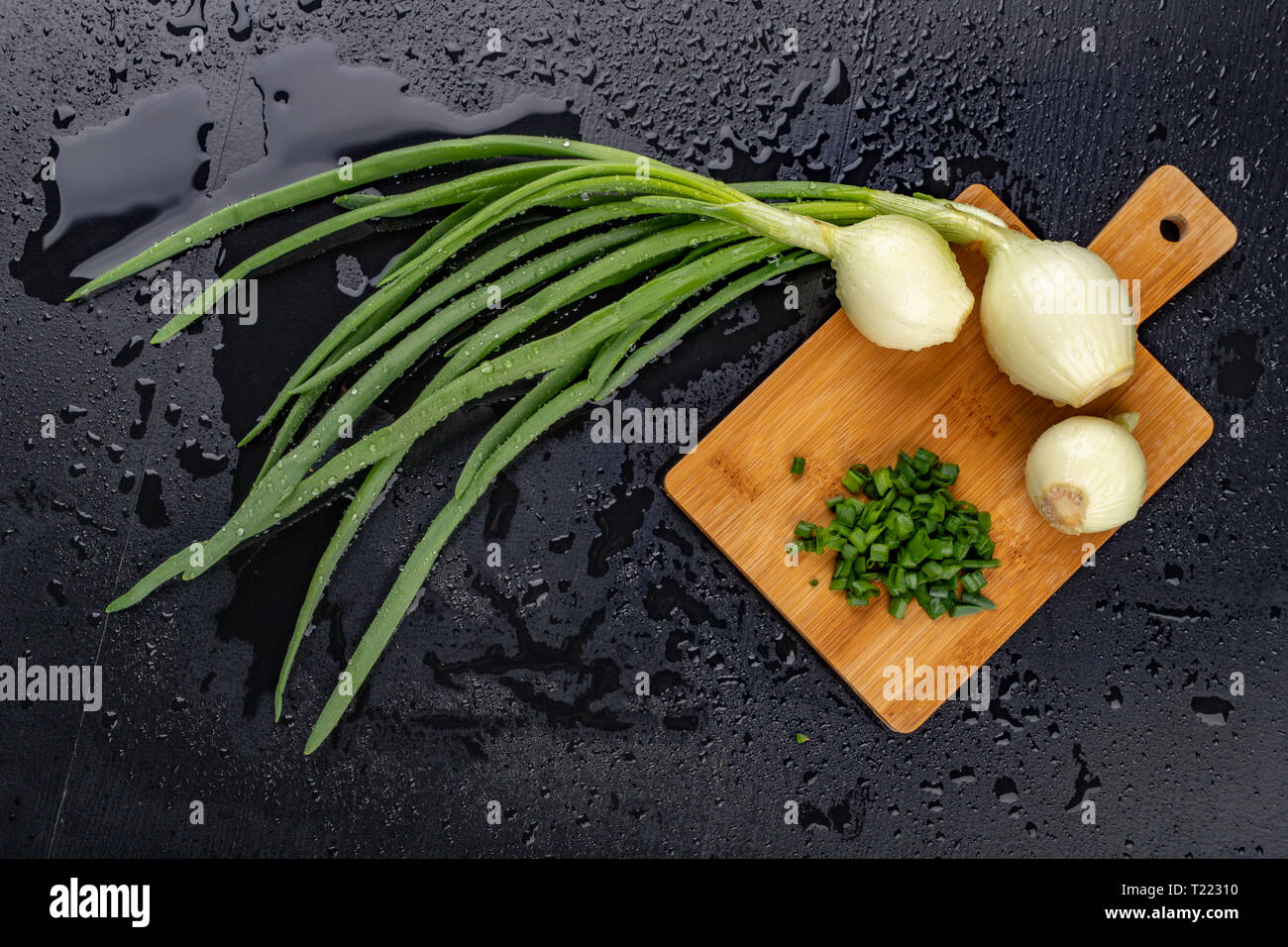 Fresh wet young onion on the kitchen table. Sliced chives on a kitchen ...