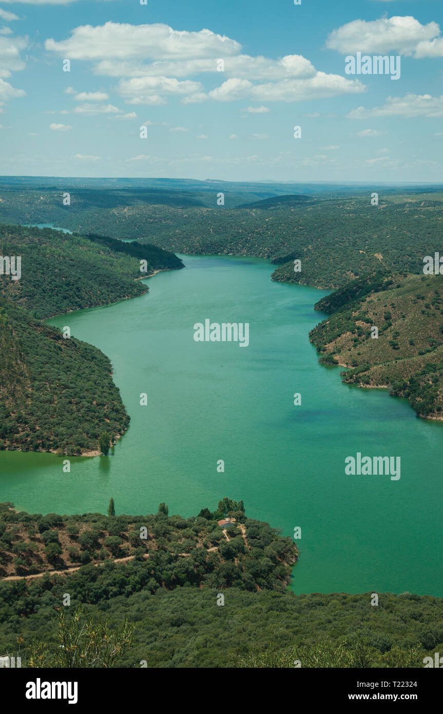Tagus River in a hilly valley with trees and house at the Monfrague ...
