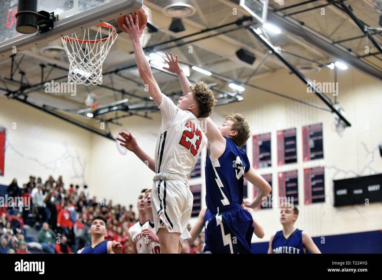 Player taking the ball to rim of the hoop while pursued an opposing ...
