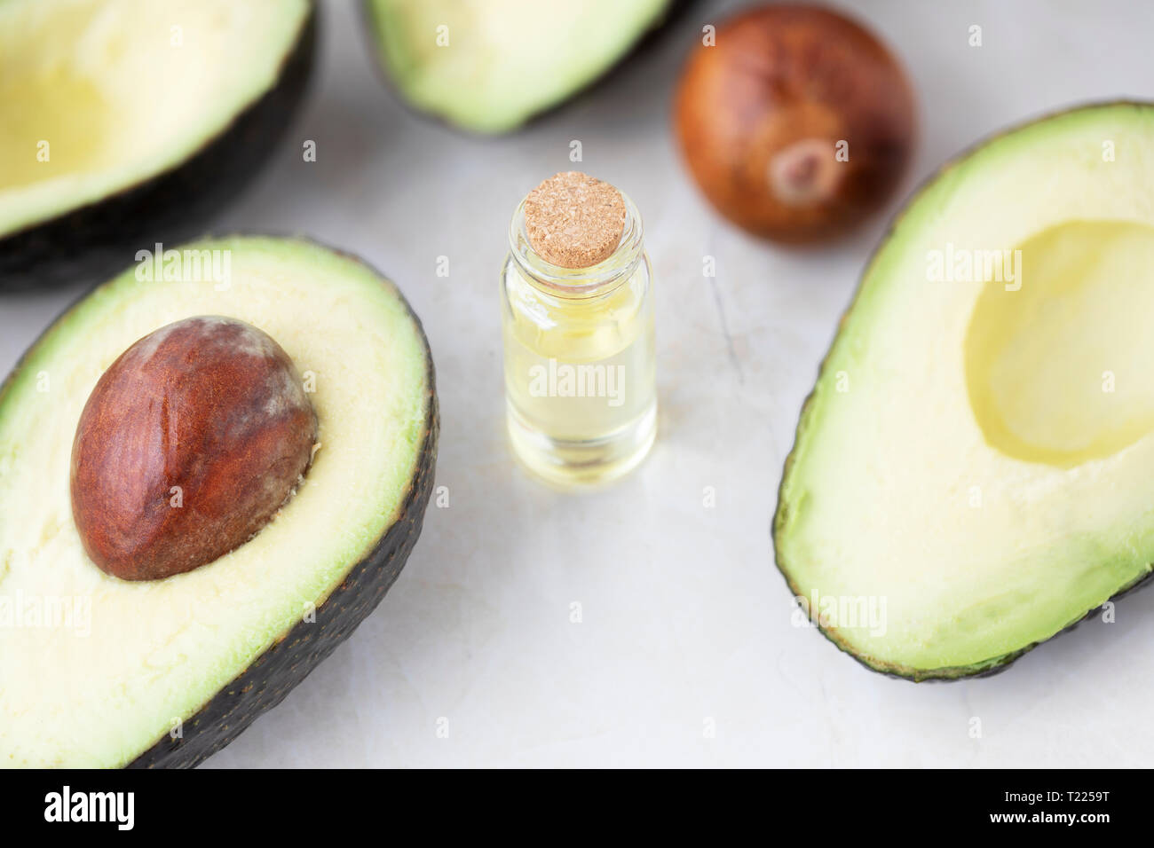 Small bottle of avocado oil and avocados on marble surface Stock Photo ...