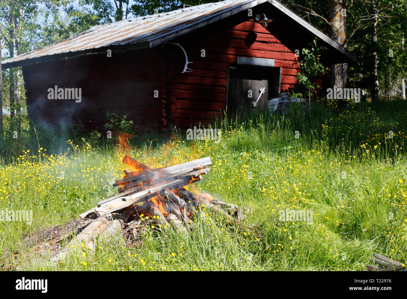 A small fire surronded by fresh grass in front of an old red barn Stock ...