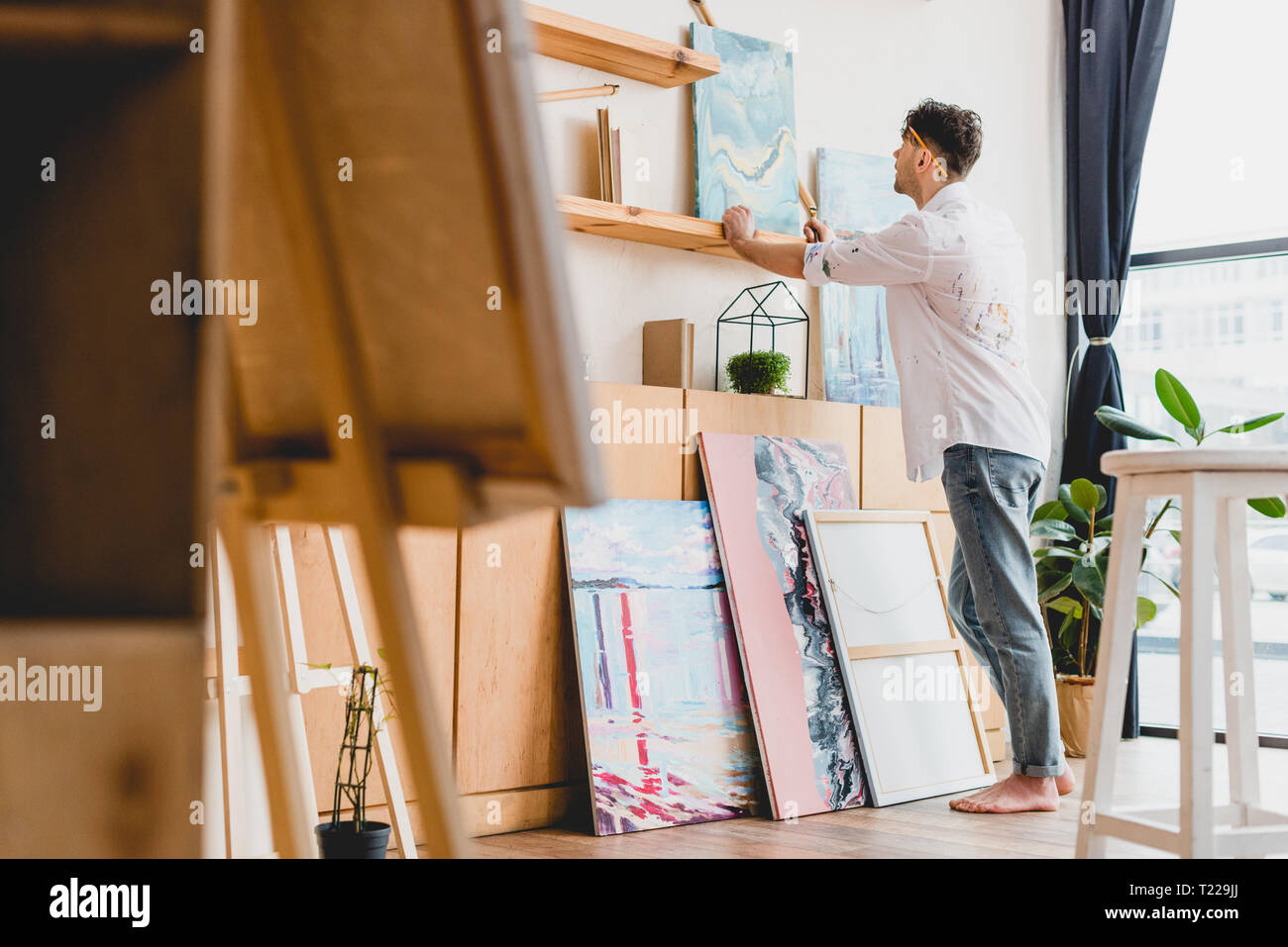 selective focus of artist in white shirt and blue jeans standing in ...
