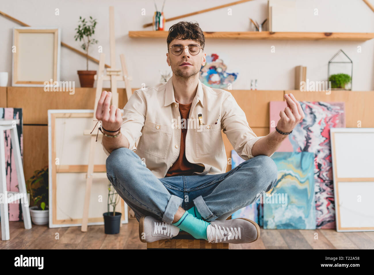 dreamy artist with closed eyes sitting in lotus pose in gallery Stock ...