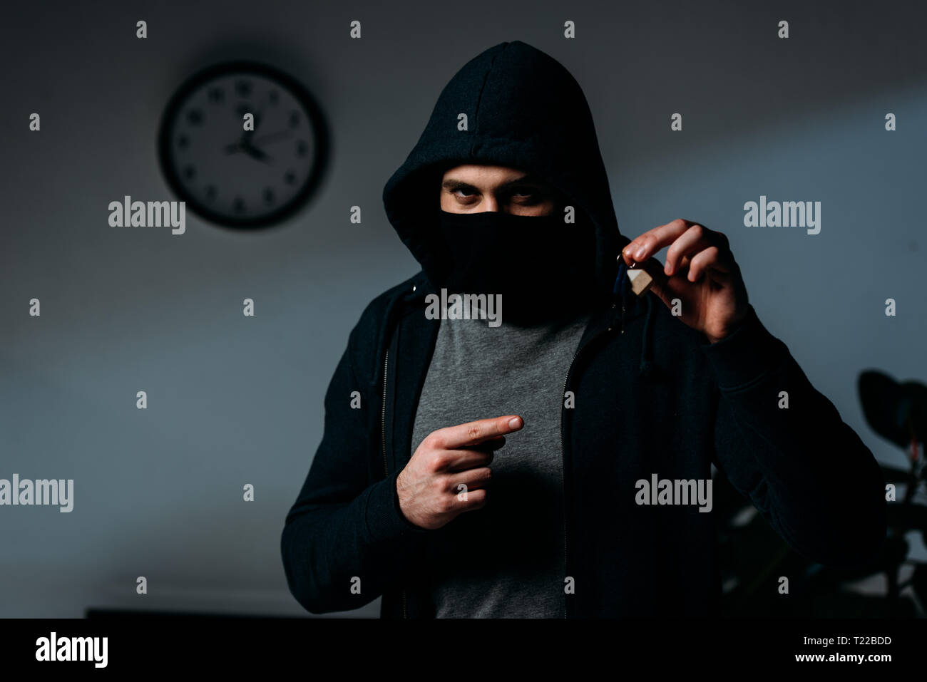 Sly thief in mask pointing with finger at keys Stock Photo - Alamy