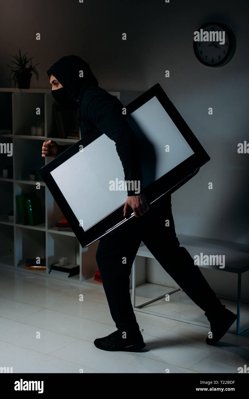 Side view of thief stealing flat-screen tv with blank screen Stock ...
